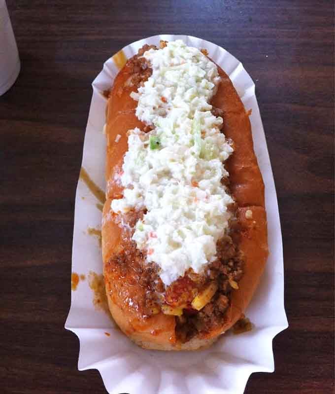 The chili slaw dog arrives looking like it survived a delicious avalanche and we're here for it.