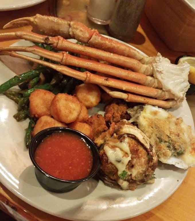 Snow crab legs, stuffed clams, and hush puppies create a plate that looks like ocean's greatest hits.