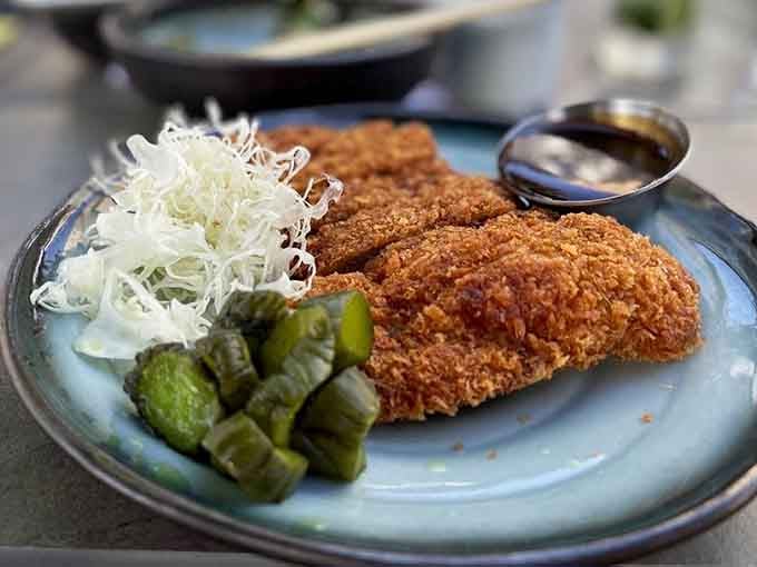 Golden-crusted chicken katsu arrives with perfectly shredded cabbage, proving that comfort food transcends all cultural boundaries beautifully.