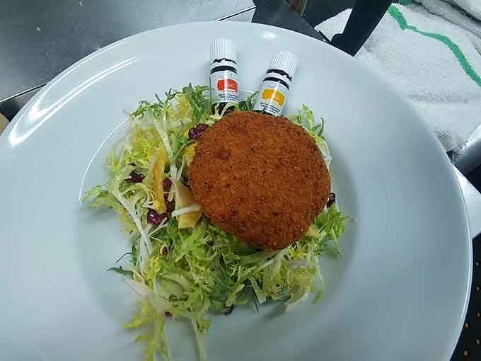 This golden-crusted crab cake sits atop fresh greens like edible treasure waiting to be discovered by your fork.