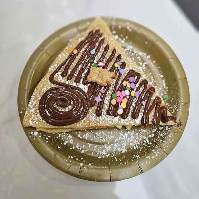 Chocolate drizzle and colorful sprinkles turn a simple crepe into edible joy that photographs itself, practically speaking.