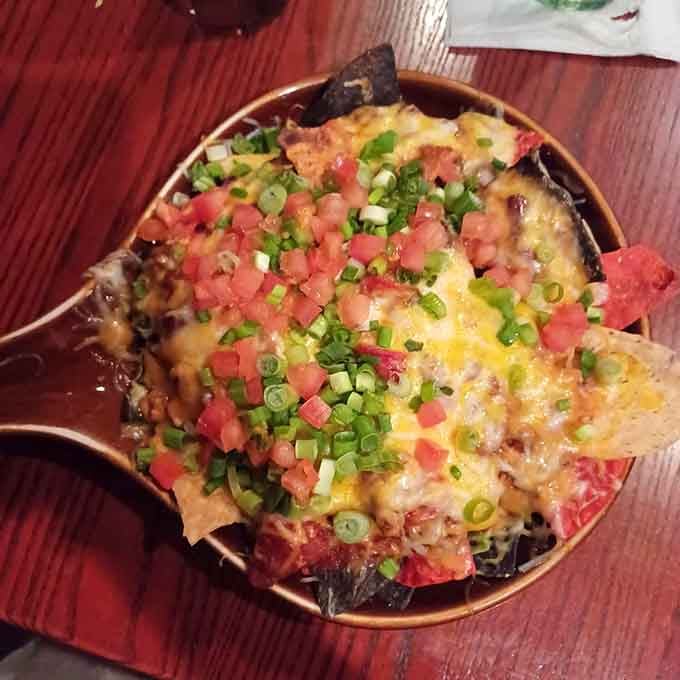 Loaded nachos piled high with cheese, tomatoes, and green onions prove appetizers here mean serious business.