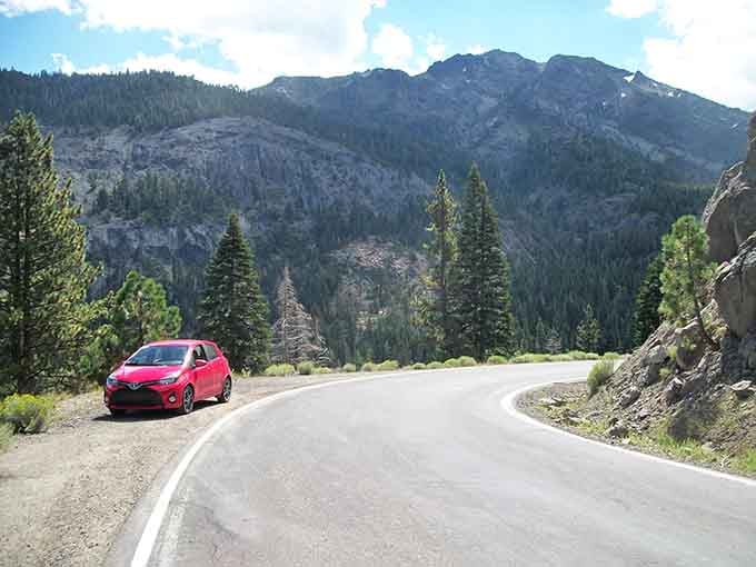 That red car knows what's up, parked at a vista where the mountains perform their daily show.