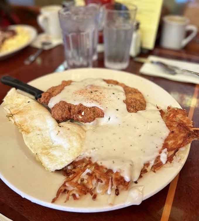 Chicken fried steak smothered in gravy with hash browns and eggs: breakfast that means serious business every single time.