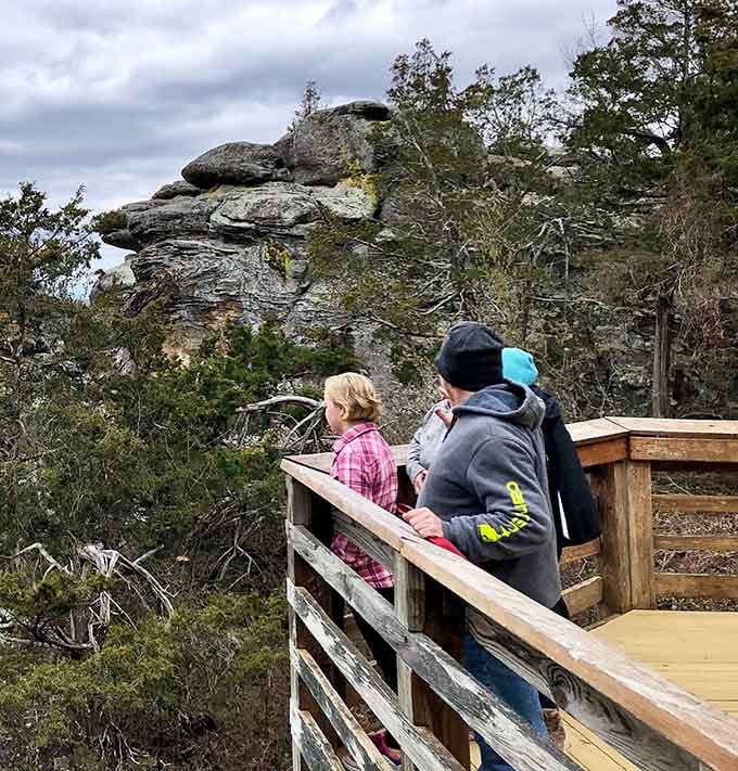 Families gather at the wooden observation deck, sharing quiet moments while ancient rocks stand guard over endless forest.
