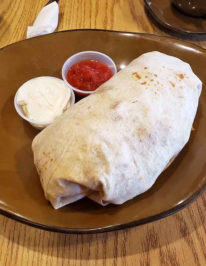 This breakfast burrito arrives plump and golden, flanked by salsa and sour cream like the perfect morning companions.