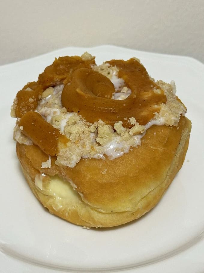 This pumpkin cream cheese roll looks like autumn decided to throw a party on top of a donut.