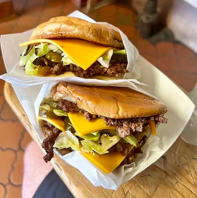 Two glorious towers of beef, cheese, and pickles wrapped in paper like edible presents you give yourself.