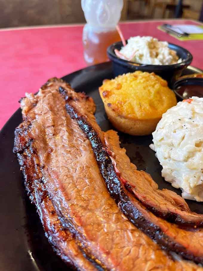 Those glistening ribs with their caramelized bark paired with golden cornbread and creamy sides are pure comfort perfection.
