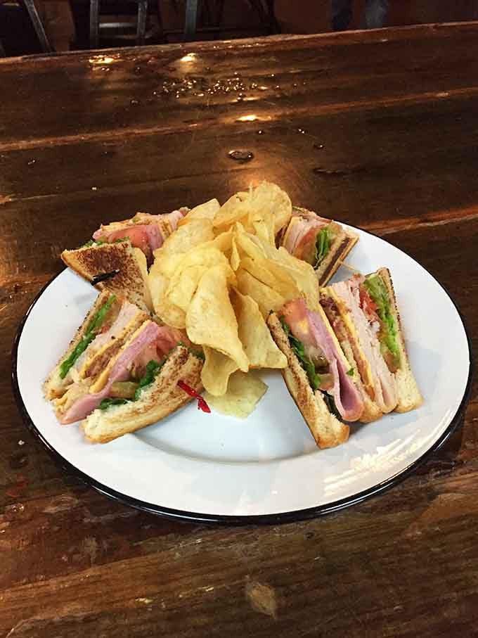 This triple-decker masterpiece comes with chips because even sandwiches need a proper supporting cast of characters.