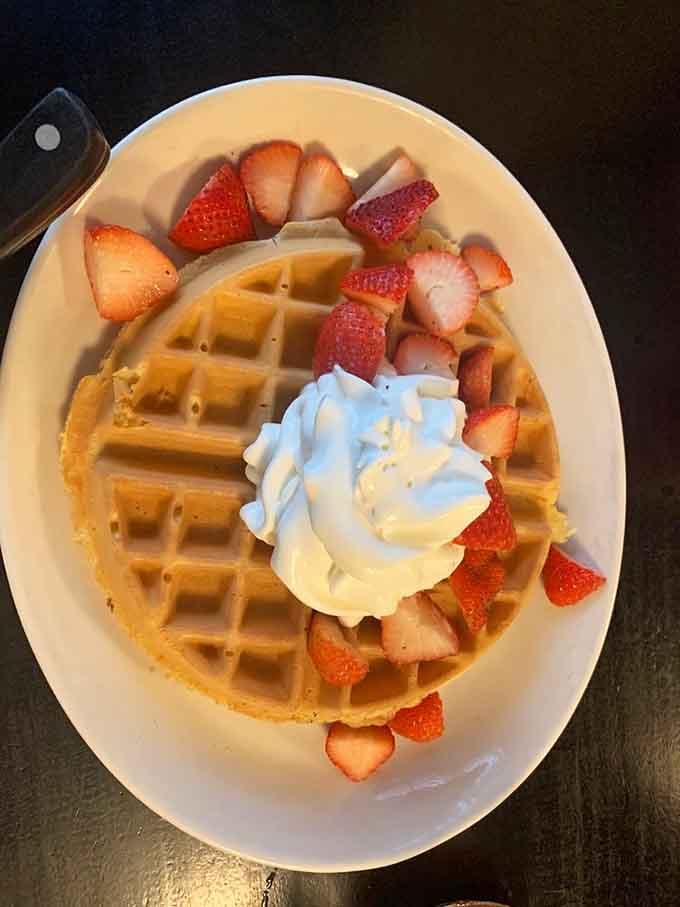 Belgian waffle topped with strawberries and whipped cream, because sometimes breakfast should feel like a celebration.