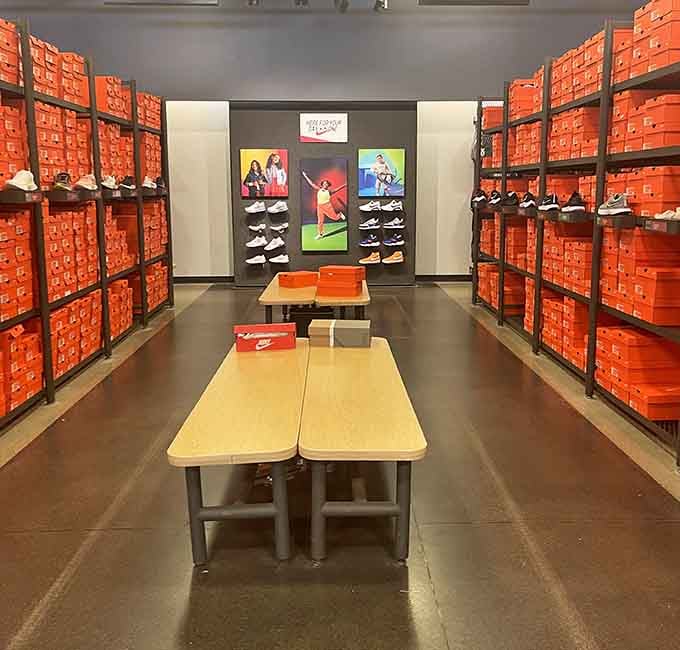 Orange Nike boxes stacked to the ceiling like a sneakerhead's fever dream, each one promising comfort without the financial pain.