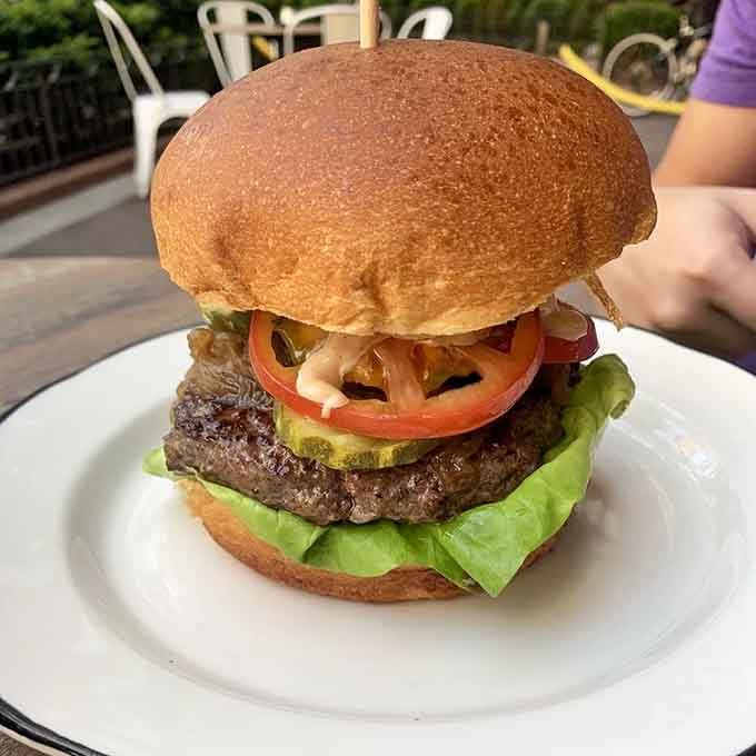 Behold the burger that requires architectural engineering to eat, stacked with fresh toppings that complement rather than compete with that Wagyu patty.