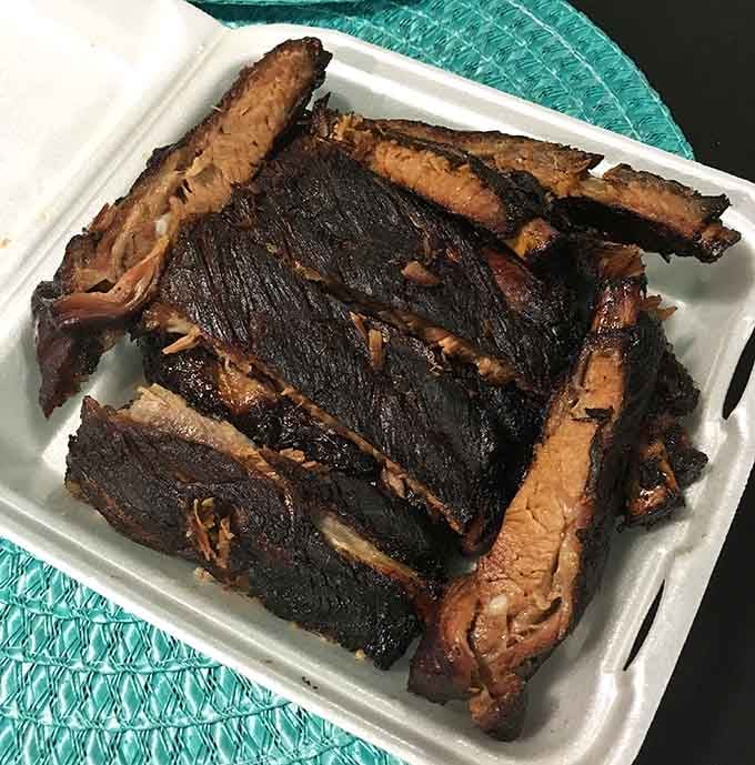 These ribs have that dark, caramelized bark that makes grown adults forget their table manners entirely.