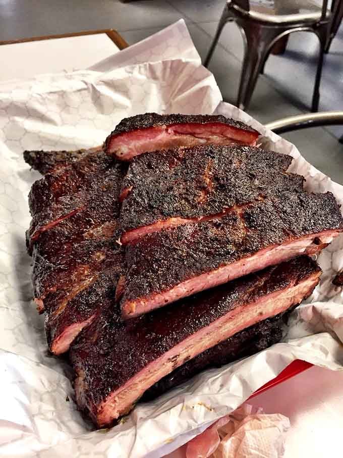 Those ribs showcase a smoke ring so perfect it belongs in a barbecue hall of fame somewhere.