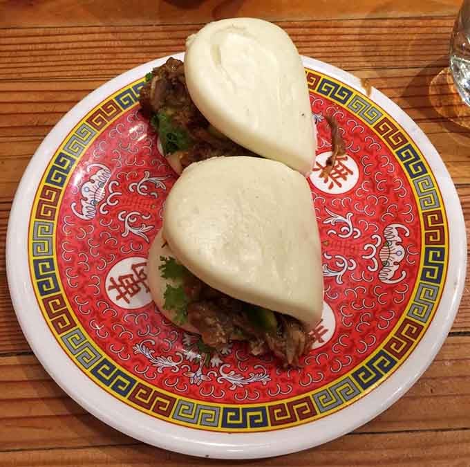 Pillowy steamed buns cradling savory filling on that classic red plate spell pure comfort food bliss.