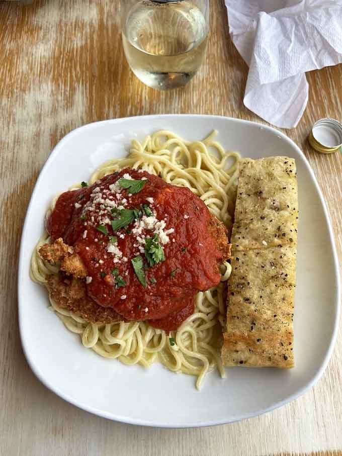 Golden-crusted chicken parmesan sits atop spaghetti like it's posing for its own cooking show debut.