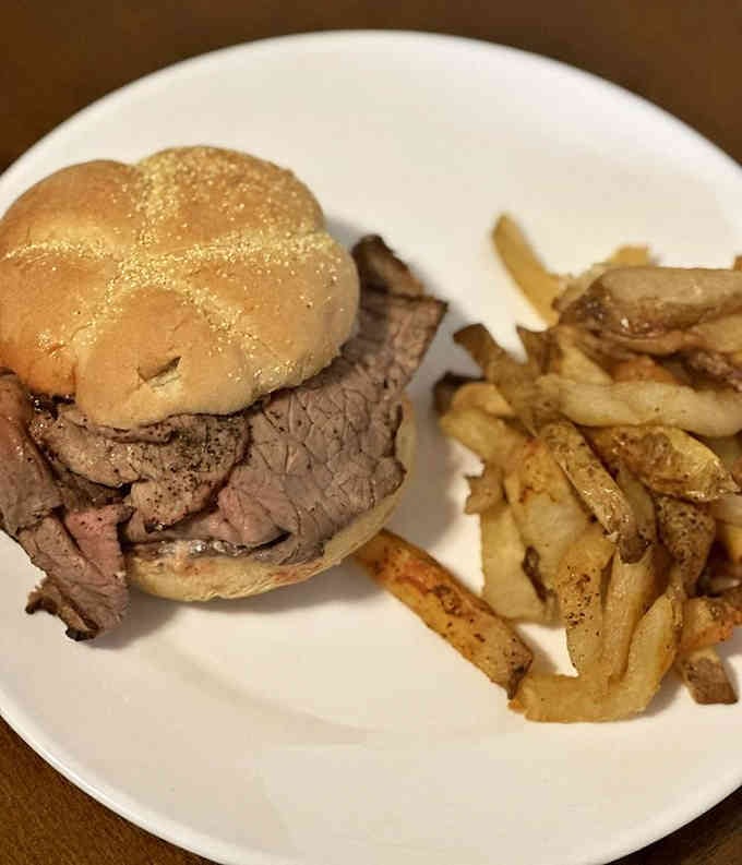 A Kaiser roll barely containing its beefy cargo, with fries standing by like delicious reinforcements.