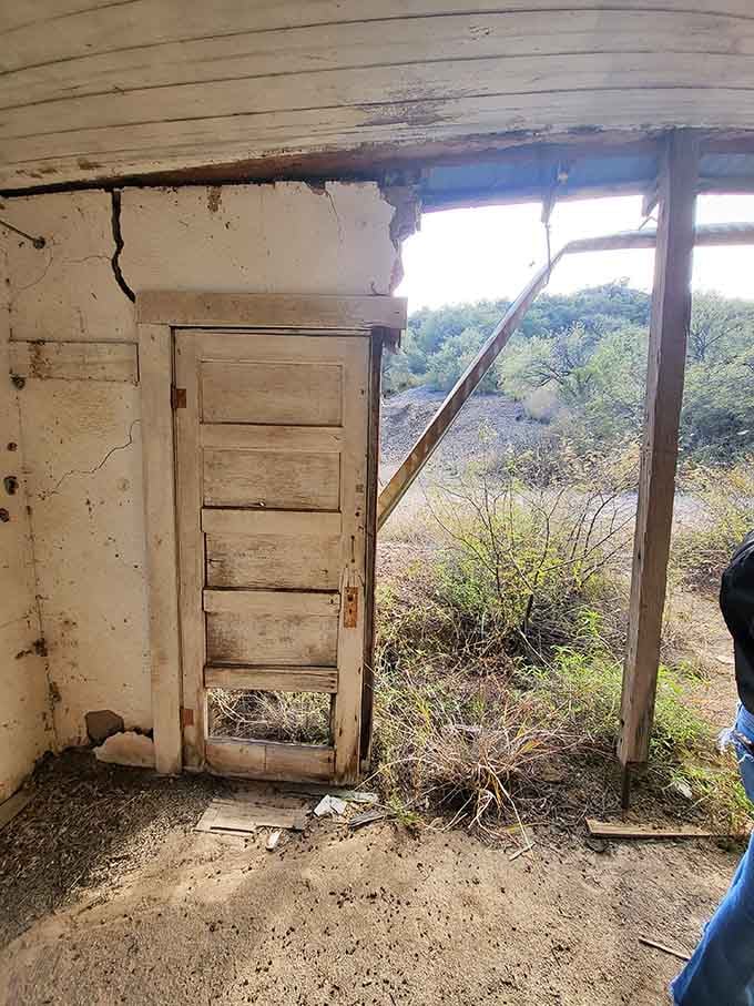 Peering through collapsed walls reveals the desert's patient work, slowly erasing human ambition one timber at a time.