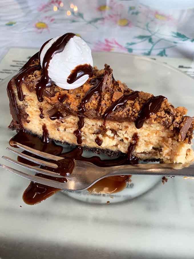 Butterfinger cheesecake drizzled with chocolate and crowned with whipped cream - because sometimes more is absolutely, gloriously more.
