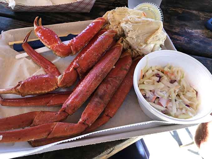 Snow crab legs piled high with coleslaw and butter, because sometimes the simplest presentations are the most spectacular feasts.