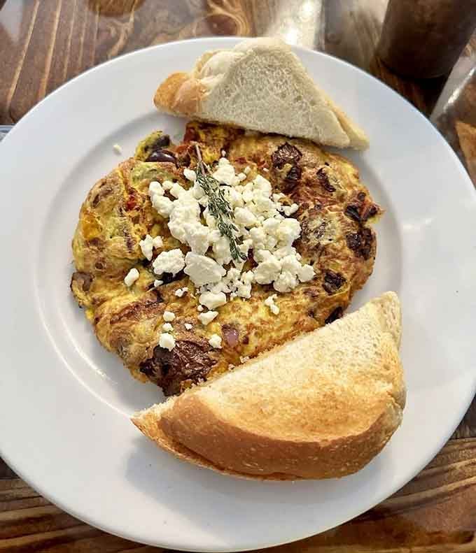 Golden frittata topped with crumbled cheese proves that simple ingredients become magic in the right hands.