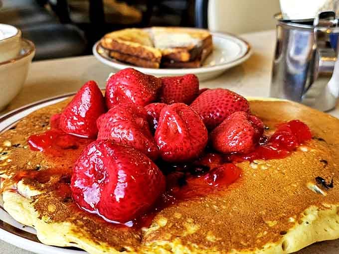 Those strawberries are practically doing synchronized swimming on a pancake the size of a manhole cover.