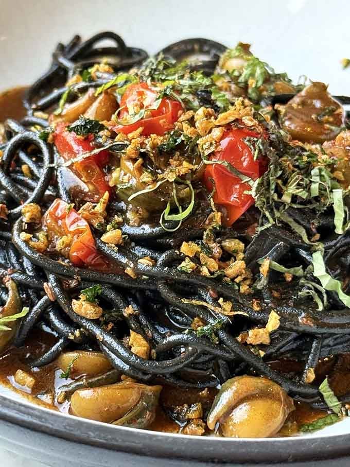 Squid ink pasta delivers drama on the plate, dark strands glistening with flavor that defies expectations.
