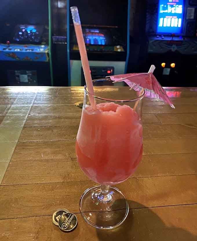 That pink umbrella suggests this cocktail takes its tropical vacation vibes seriously, arcade games not included but highly recommended.