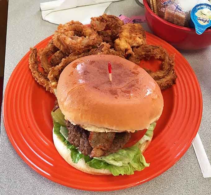 That burger sits like a delicious skyscraper next to onion rings so perfectly golden they deserve their own spotlight.