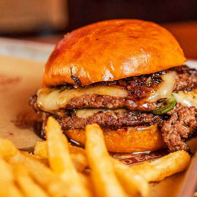 This towering double-patty masterpiece with melted cheese proves that sometimes more is absolutely, positively more in the best way.