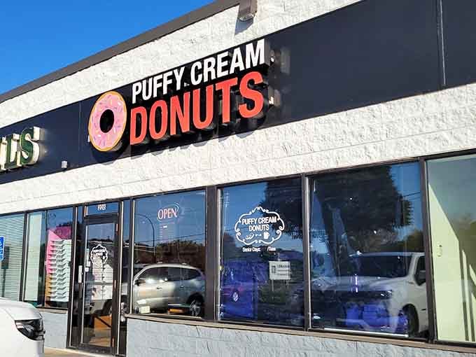 That giant pink donut sign is like a lighthouse guiding hungry travelers to their sweet, sugary destination.