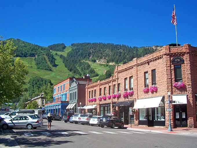 Bright flower boxes dress up brick facades as summer mountains show off their green slopes behind town.