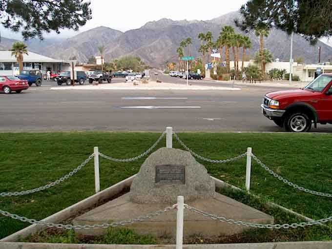 A historic marker anchors this desert crossroads where mountains meet sky in spectacular fashion daily.