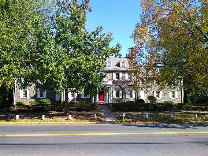 Mature trees frame this stately home's classic facade, where autumn colors hint at the changing seasons and timeless architecture.