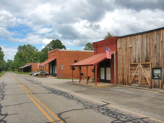 Weathered storefronts and that lonely American flag create a scene straight from a Western ghost town movie set.