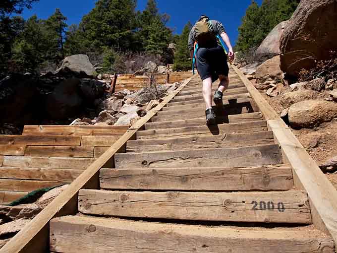 A hiker powers up the steep incline, legs pumping hard as the relentless stairs climb toward distant peaks and glory.