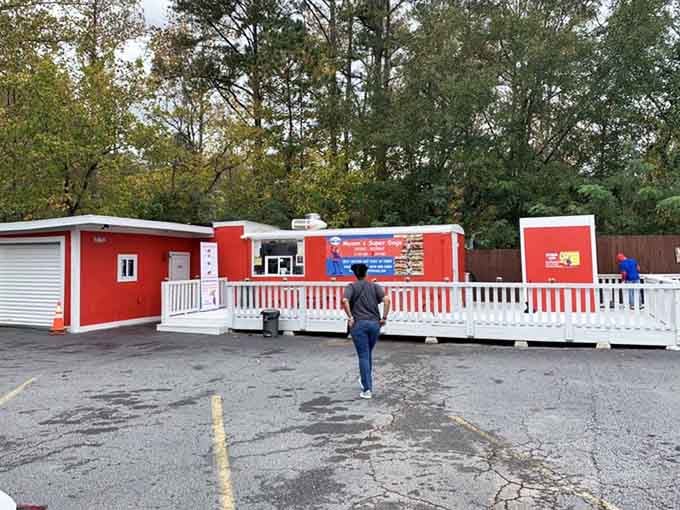 Someone's walking toward hot dog heaven at this vibrant red stand where innovation meets classic American comfort food perfectly.