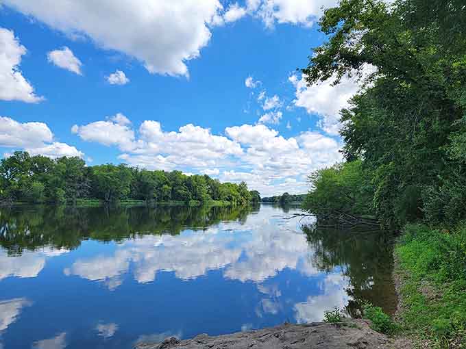 Clouds mirror perfectly on glass-smooth water, creating a scene so serene it could lower your blood pressure instantly.