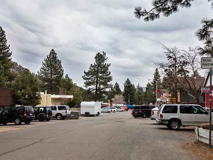 Rustic cabins and colorful storefronts create a storybook setting where flags wave and hungry visitors find genuine mountain cooking.
