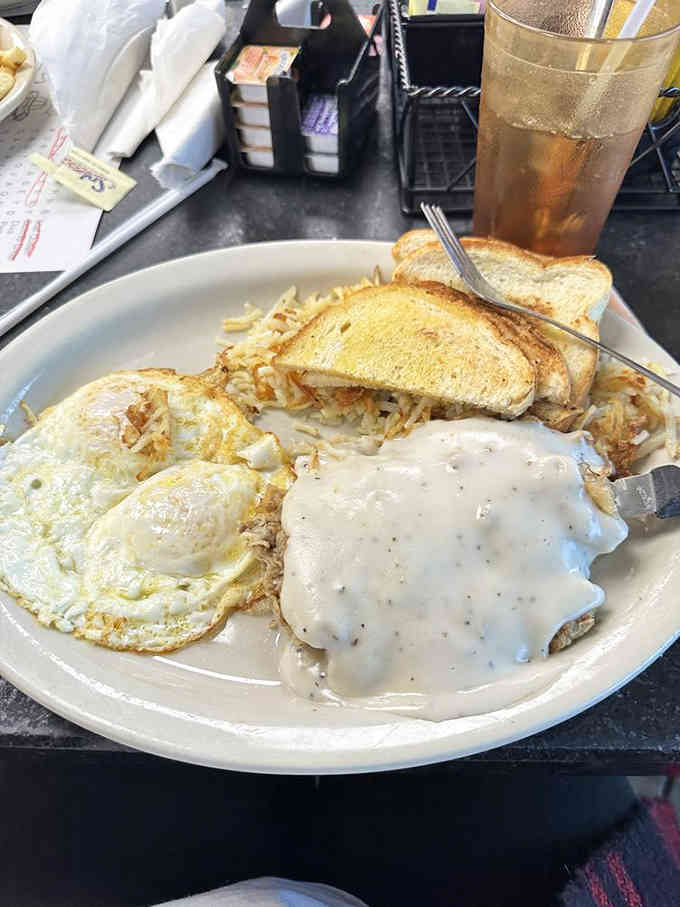 Chicken fried steak drowning in cream gravy alongside perfectly fried eggs is Texas breakfast poetry on a plate.