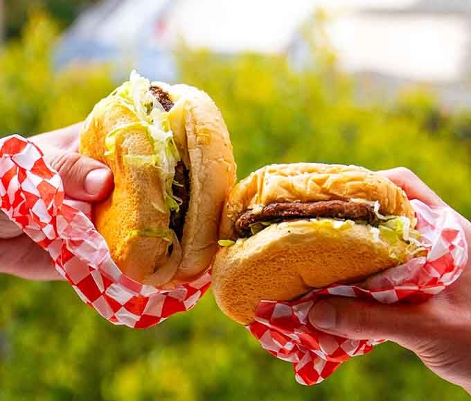 Two burgers wrapped in checkered paper, ready to make your day infinitely better than it was five minutes ago.