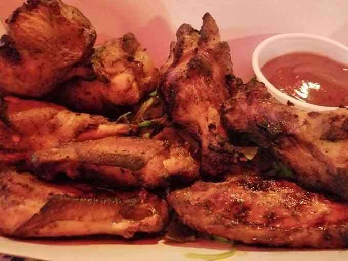 Golden-brown wings piled high with sauce on the side, looking like they just won best supporting actor at dinner.