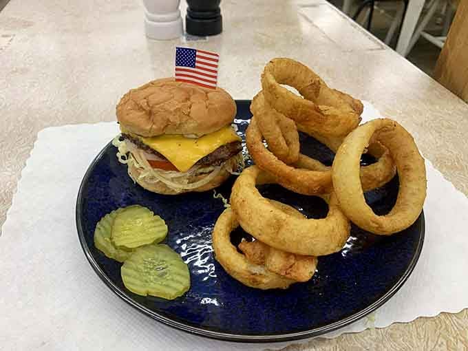 That burger wears its American flag with pride, surrounded by golden onion rings begging to be devoured immediately.