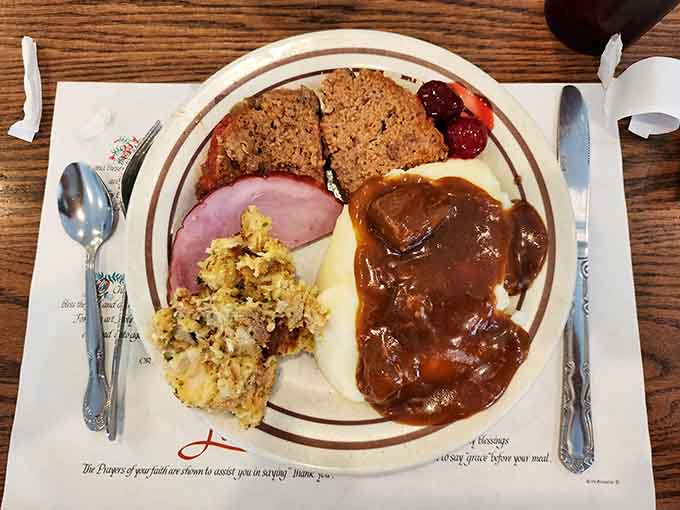 Meatloaf smothered in gravy alongside ham and stuffing proves that sometimes more really is more on one plate.
