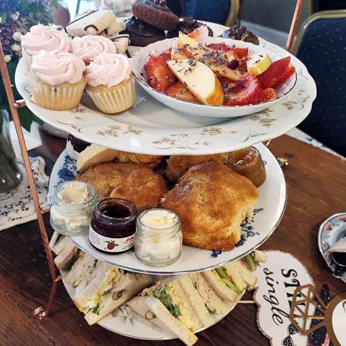 Three tiers of pure joy: finger sandwiches, warm scones with clotted cream, and sweets that look almost too pretty to eat.