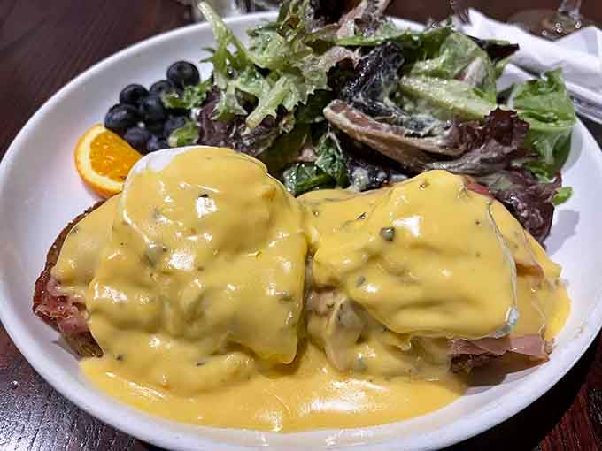 That hollandaise sauce is cascading like a delicious yellow waterfall over perfectly poached eggs and greens.