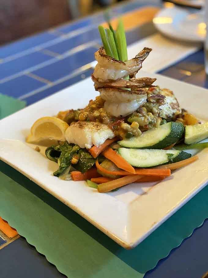 Grilled halibut topped with shrimp over vegetables so colorful they look like they're auditioning for a cooking show.