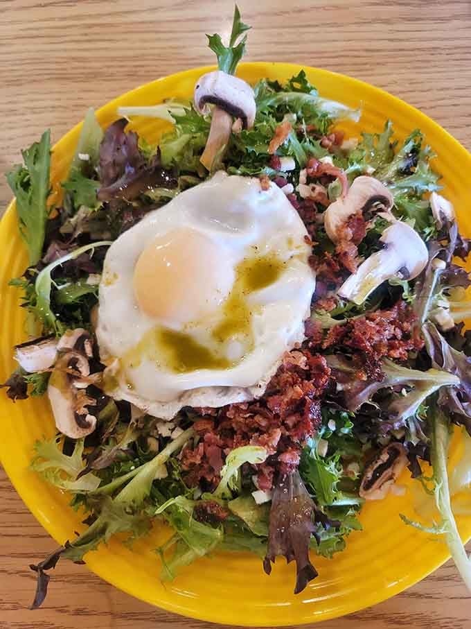 A basted egg crowns this breakfast salad like edible sunshine, mixing greens with bacon and mushrooms beautifully.