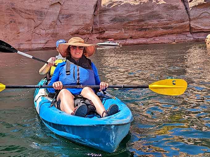 Ready for launch: colorful kayaks lined up like a rainbow against ancient rock, adventure awaits.
